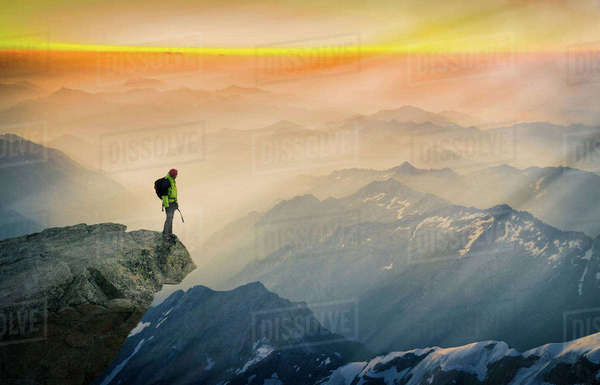 Mountain climber standing on edge of mountain, looking at view ...