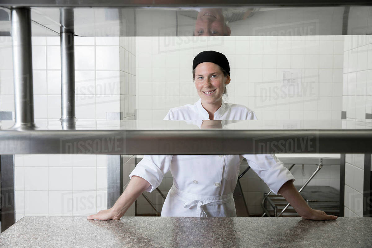 Portrait of chef in commercial kitchen looking at camera smiling ...