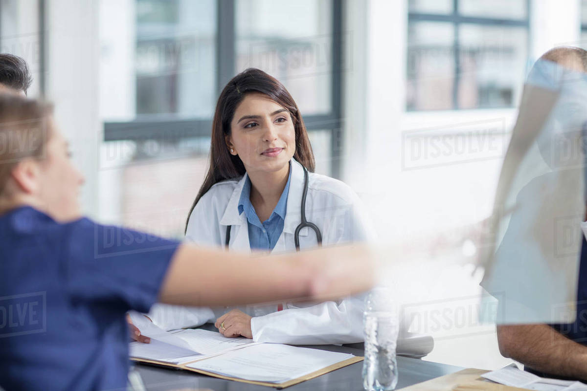 Group of doctors sitting at table, having discussion - Royalty-free ...