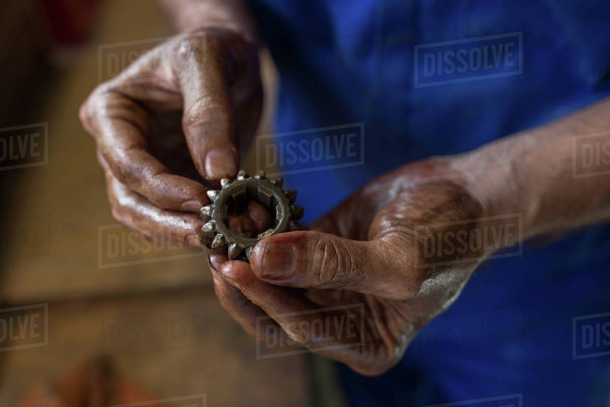 Hands of male car mechanic holding car part in repair garage - Royalty ...