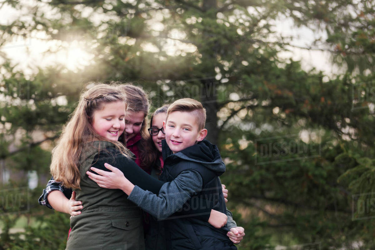 Portrait of boy and female cousins hugging in garden - Royalty-free ...