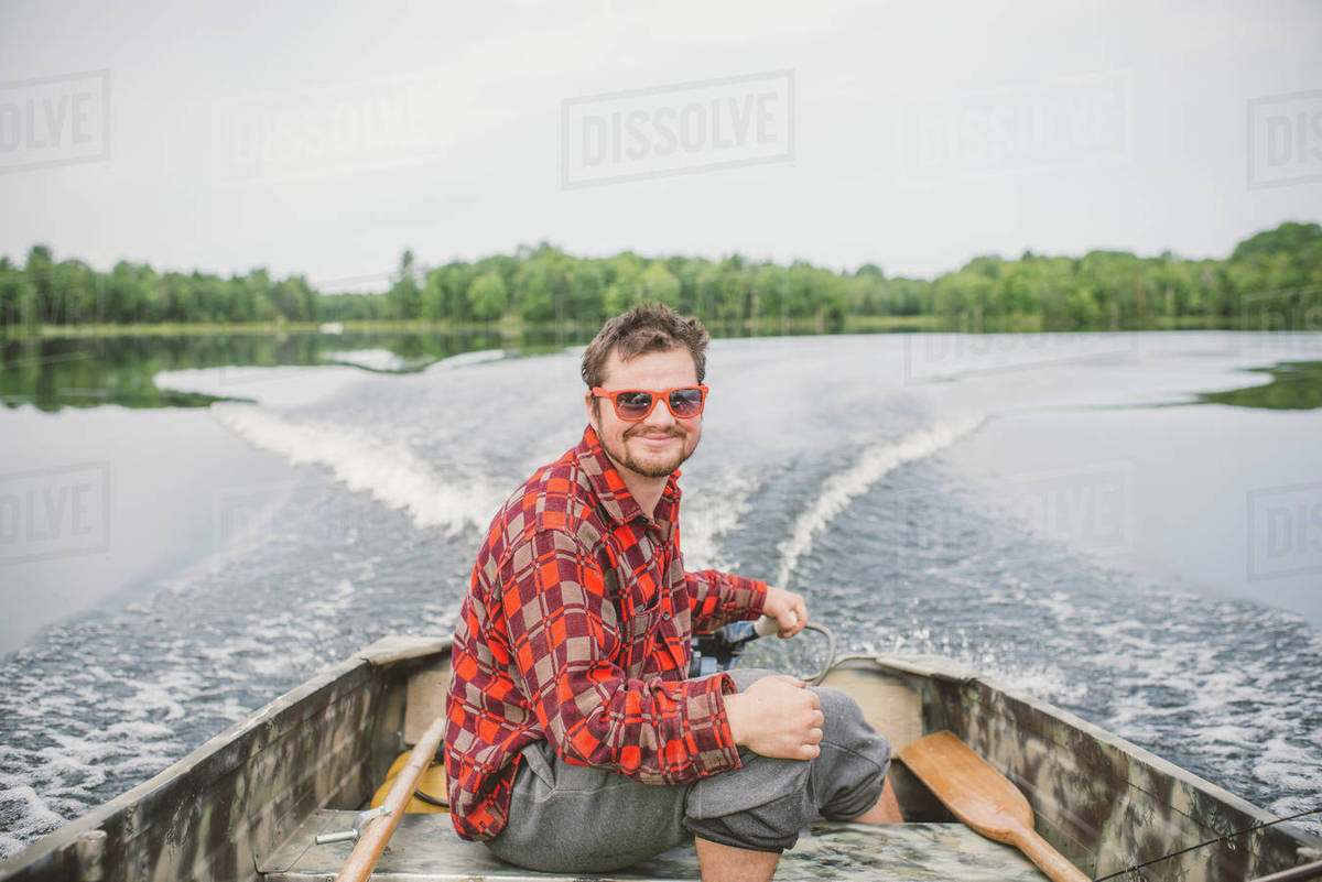 Portrait of young man in boat on lake - Stock Photo - Dissolve