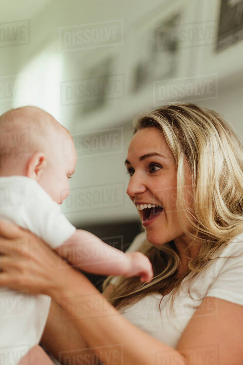 Mother smiling at baby daughter face to face - Stock Photo - Dissolve