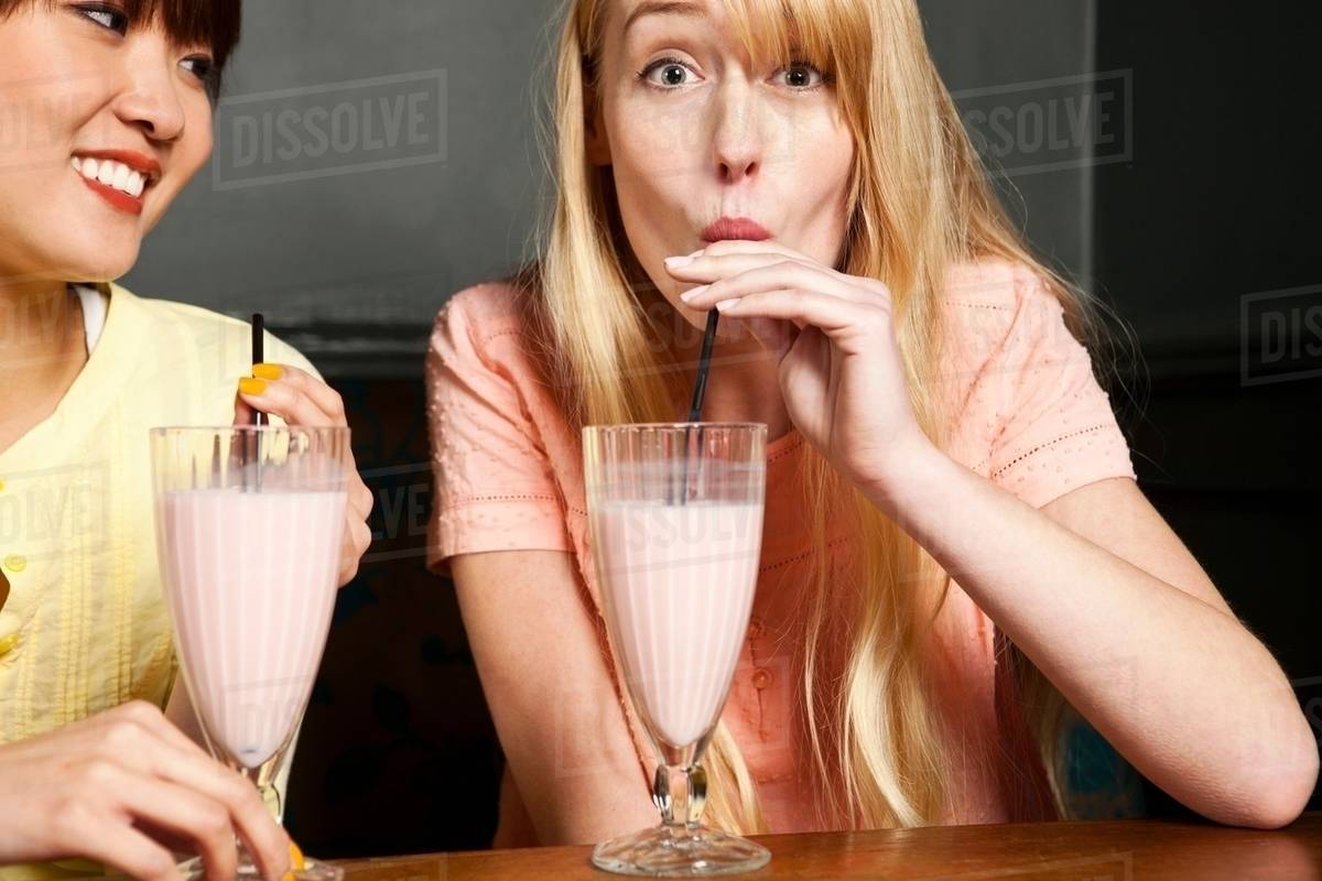 Two women drinking milkshake - Royalty-free Stock Photo | Dissolve