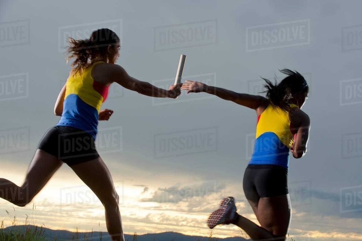 Female relay racers passing baton - Royalty-free Stock Photo | Dissolve