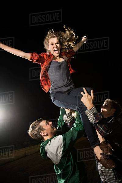 Two male friends lifting teenage girl, arms outstretched - Royalty-free ...