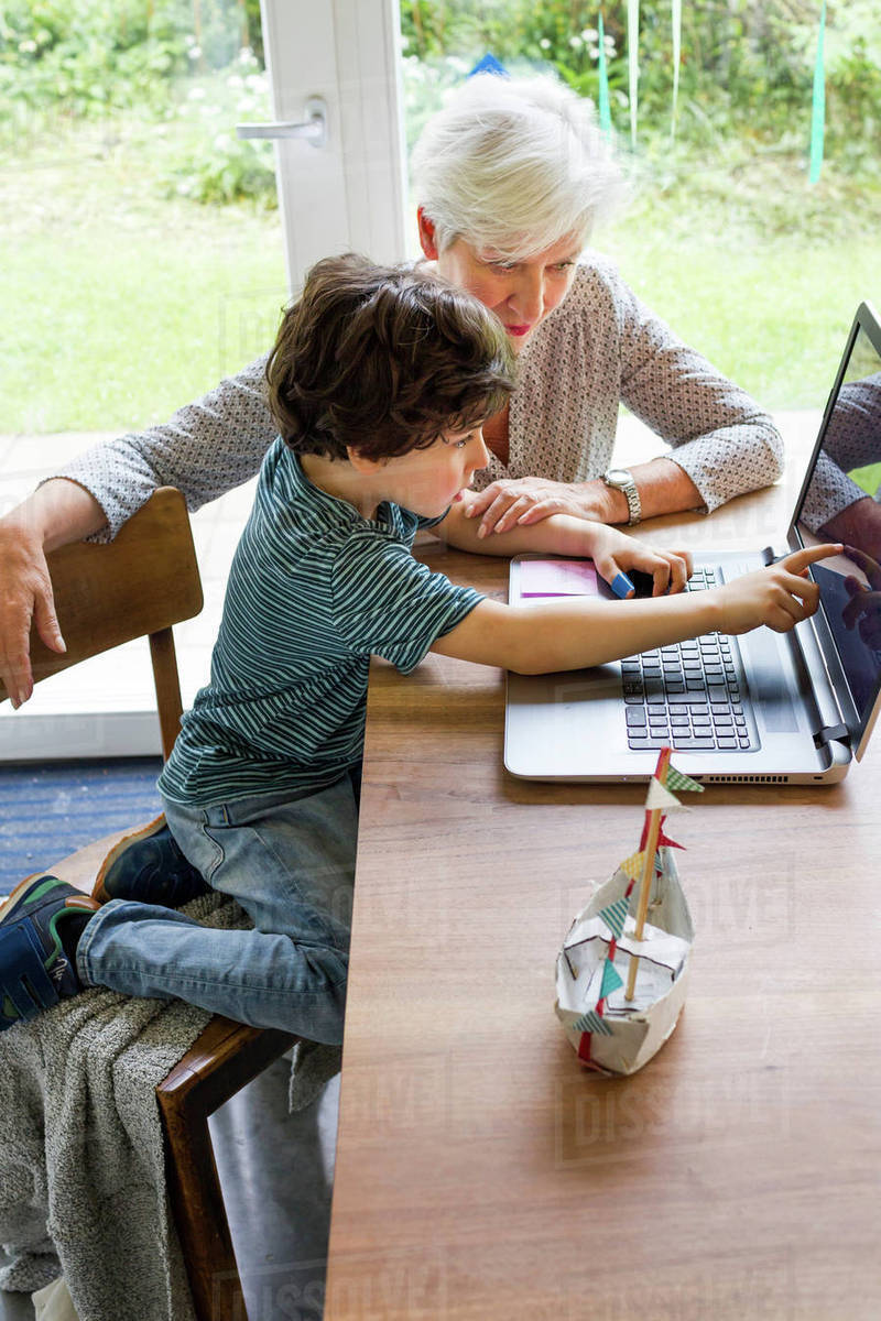 Grandmother and grandson sitting at table, using laptop - Royalty-free ...