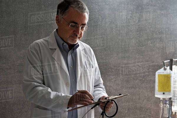 Doctor writing at medical chart - Royalty-free Stock Photo | Dissolve