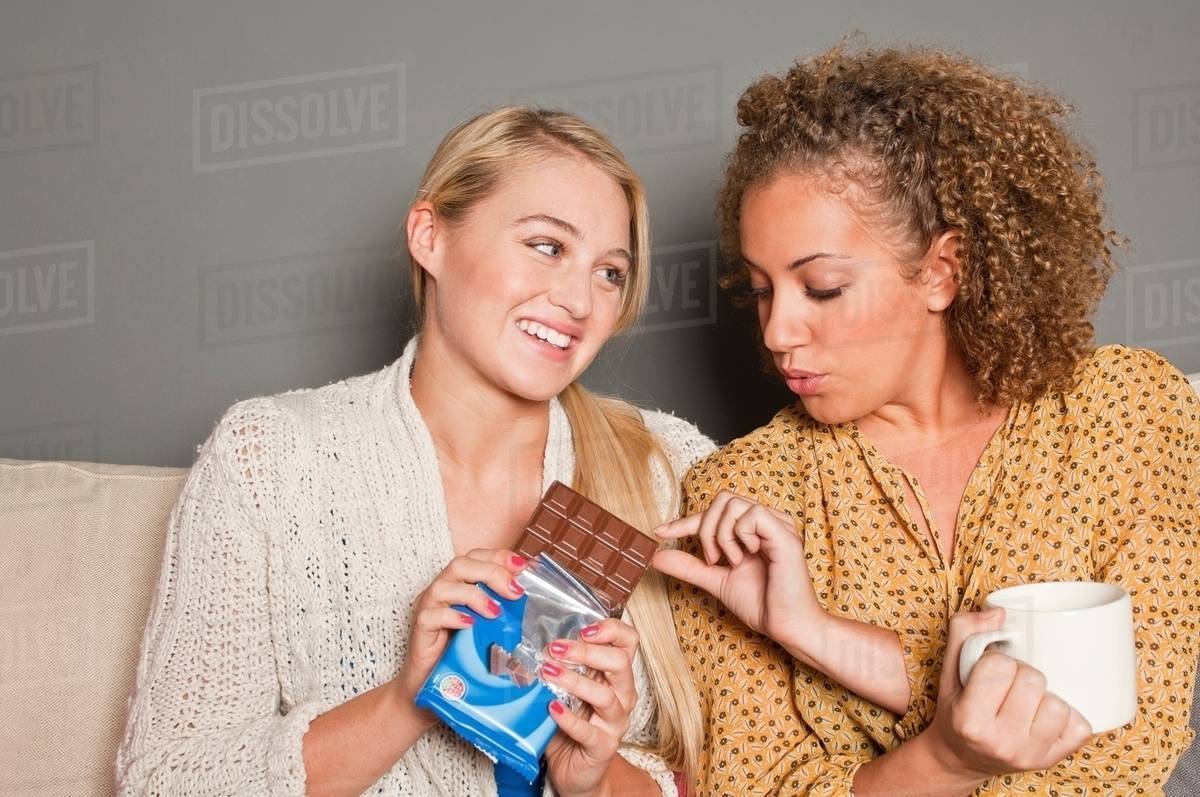 Woman offering friend chocolate - Royalty-free Stock Photo | Dissolve