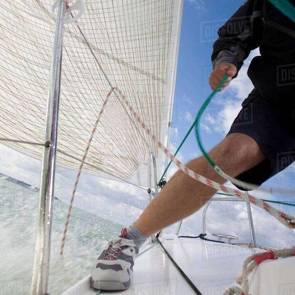Man on yacht, pulling ropes - Stock Photo - Dissolve