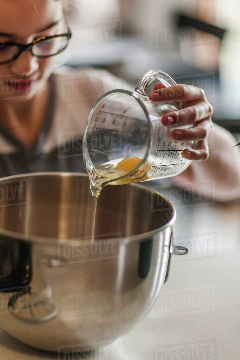 Girl pouring egg yolk into mixing bowl for christmas cookies at kitchen ...