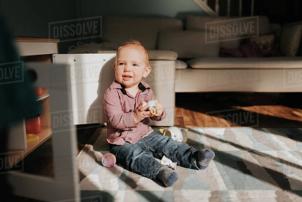Baby boy sitting playing on living room rug - Royalty-free Stock Photo ...