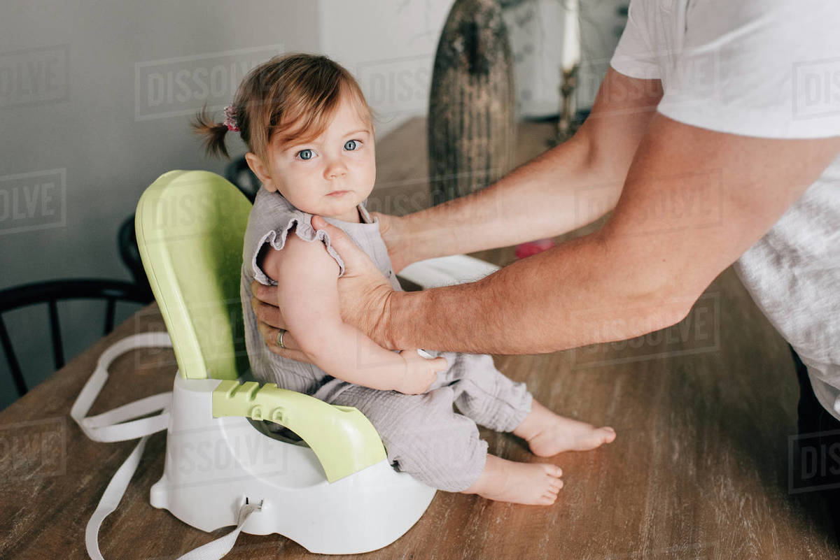 Father putting baby daughter in child seat, cropped portrait - Stock ...