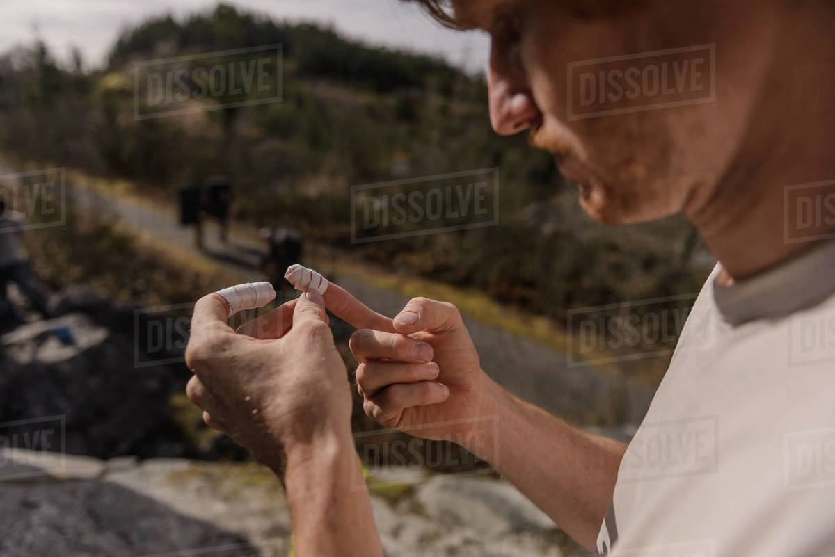 Climber taping fingers before bouldering in forest, Squamish, Canada ...