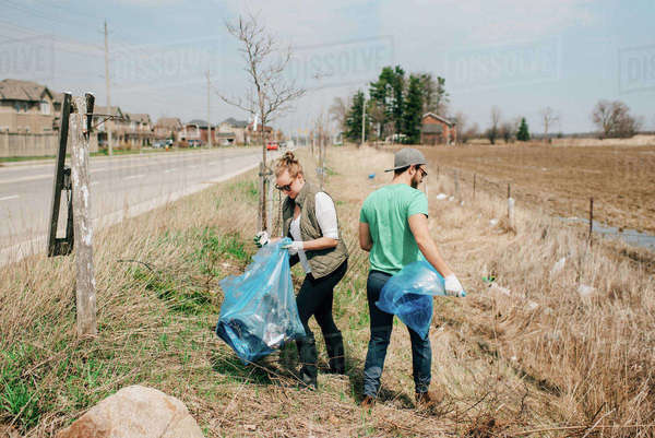 Couple picking up rubbish by roadside, Georgetown, Canada - Royalty ...