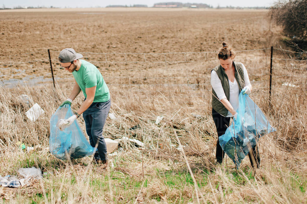 Couple picking up rubbish by field, Georgetown, Canada - Royalty-free ...