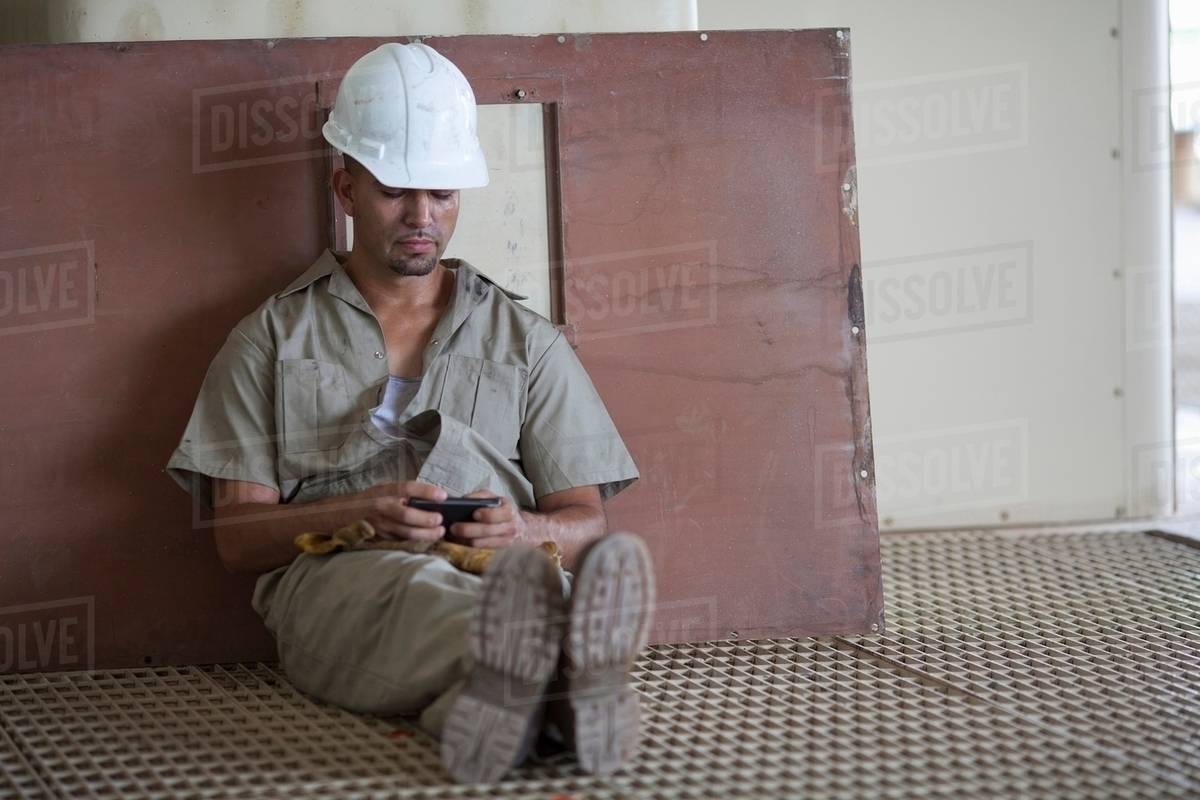 Industrial worker using cell phone - Stock Photo - Dissolve