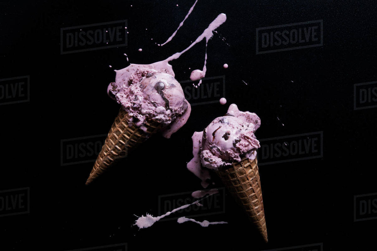 Two chocolate chip raspberry ice-cream cones with melted splash against ...