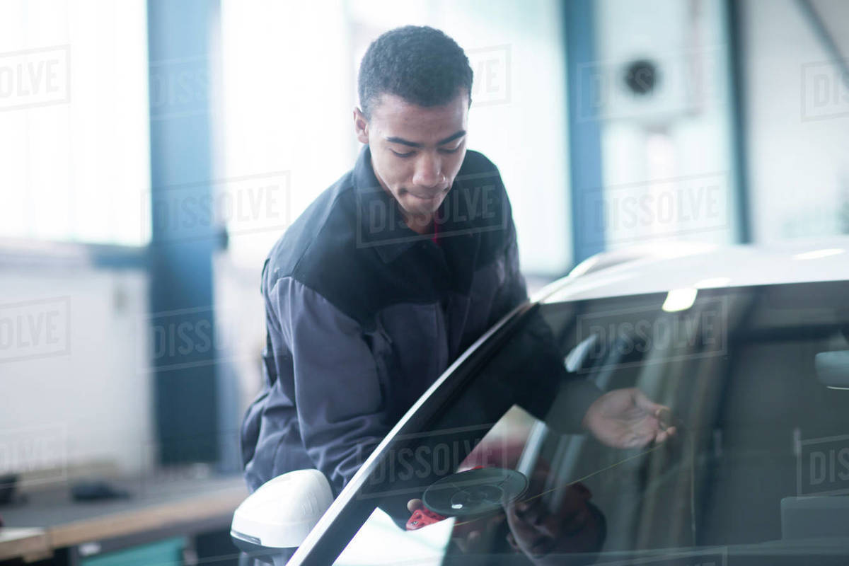Workman fixing car windshield in workshop - Stock Photo - Dissolve