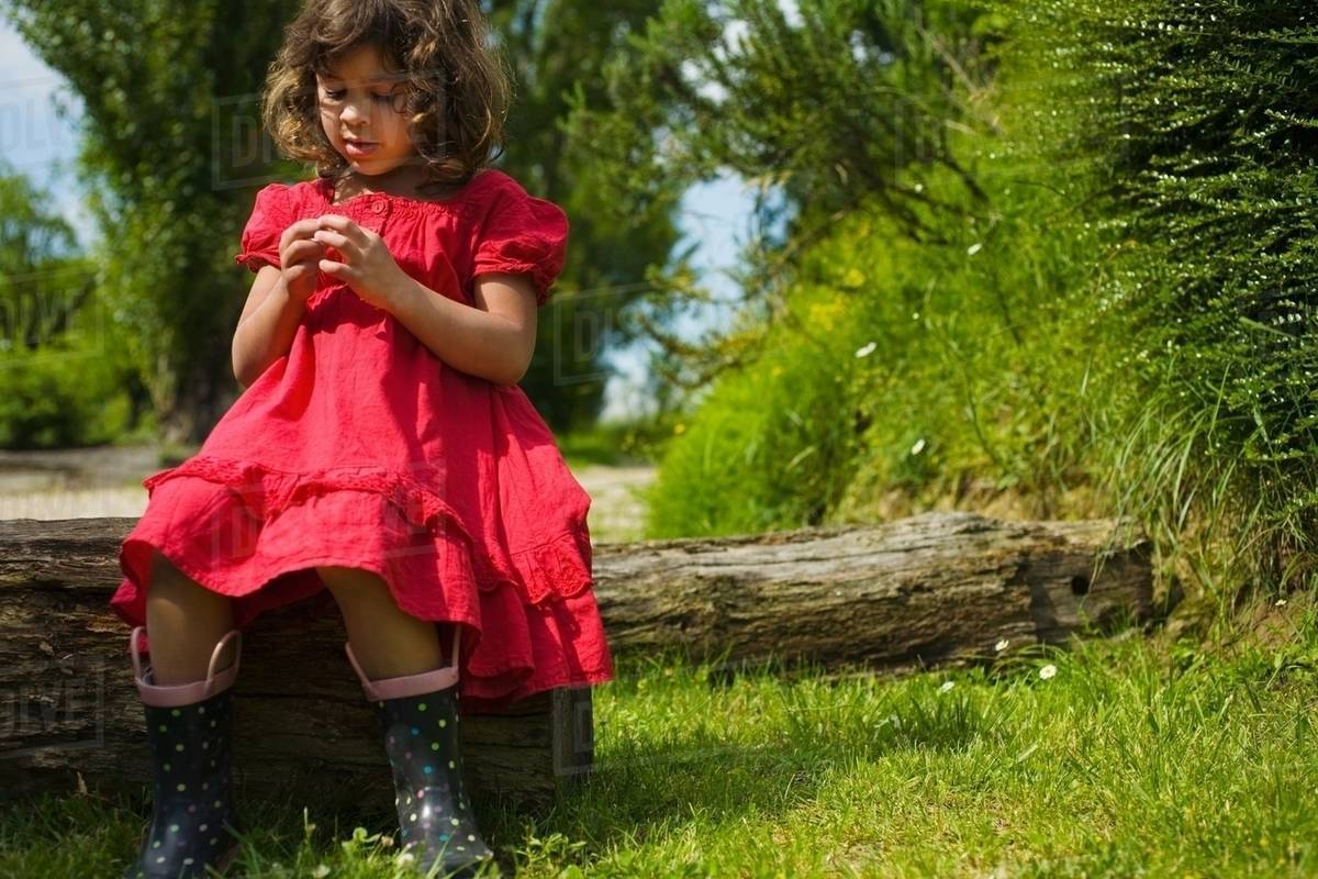 A girl sitting on a log - Stock Photo - Dissolve