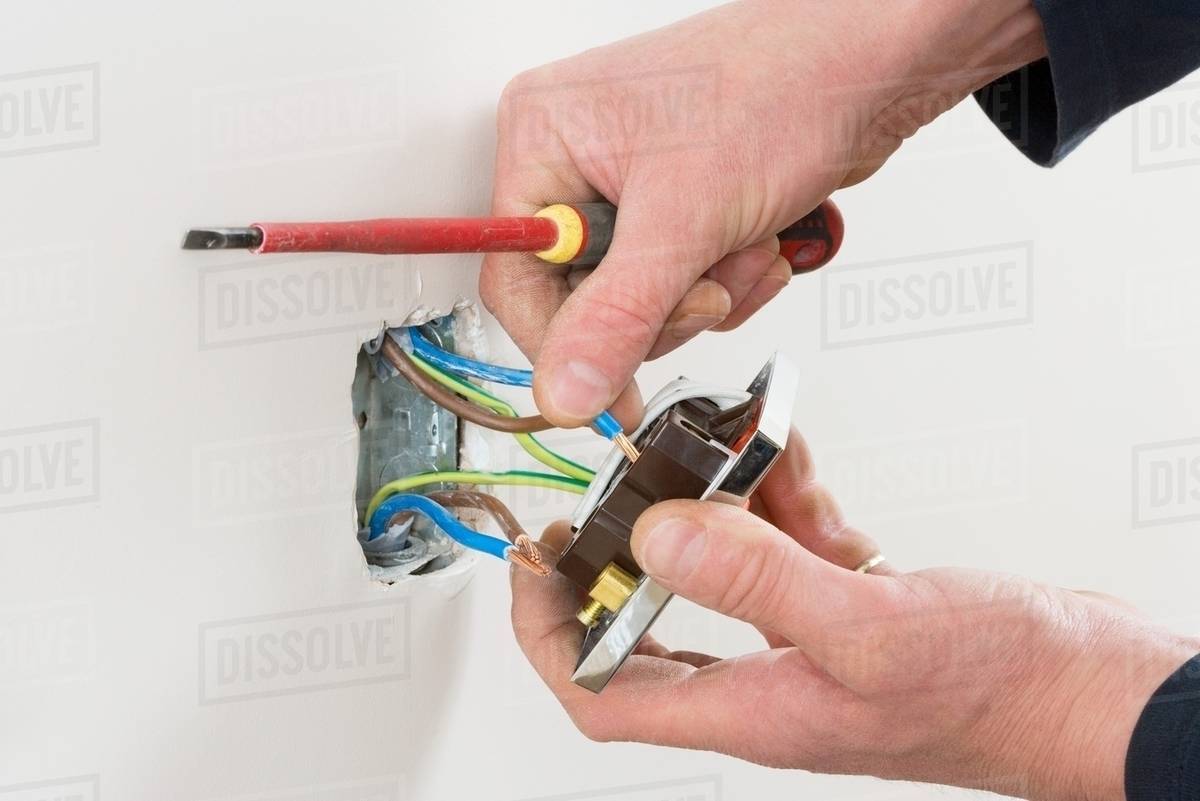 An electrician fixing a socket - Stock Photo - Dissolve