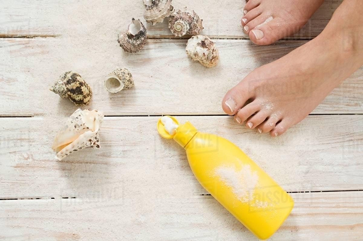 Female feet with shells and suncream - Royalty-free Stock Photo | Dissolve