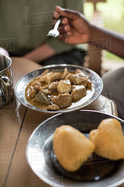 Person eating traditional African meat dish, mid section, Cotonou ...