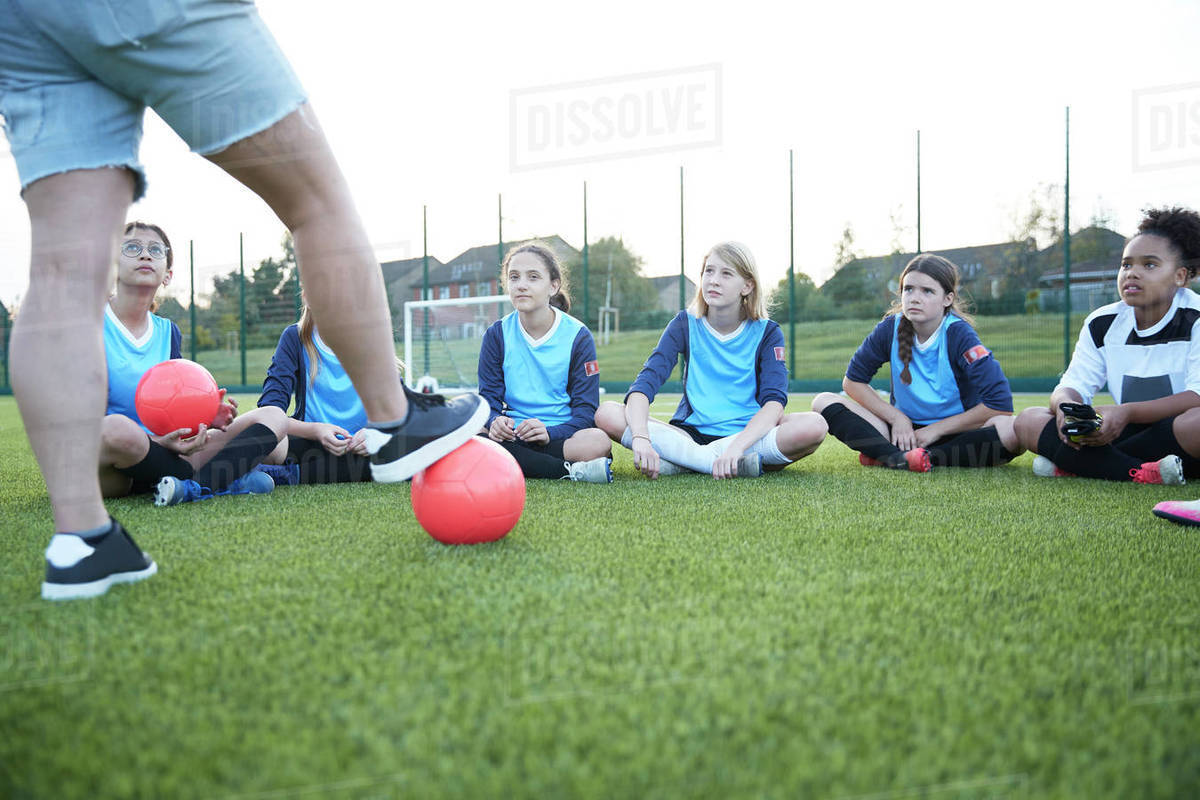 Girls' soccer team sitting in field during training - Royalty-free ...