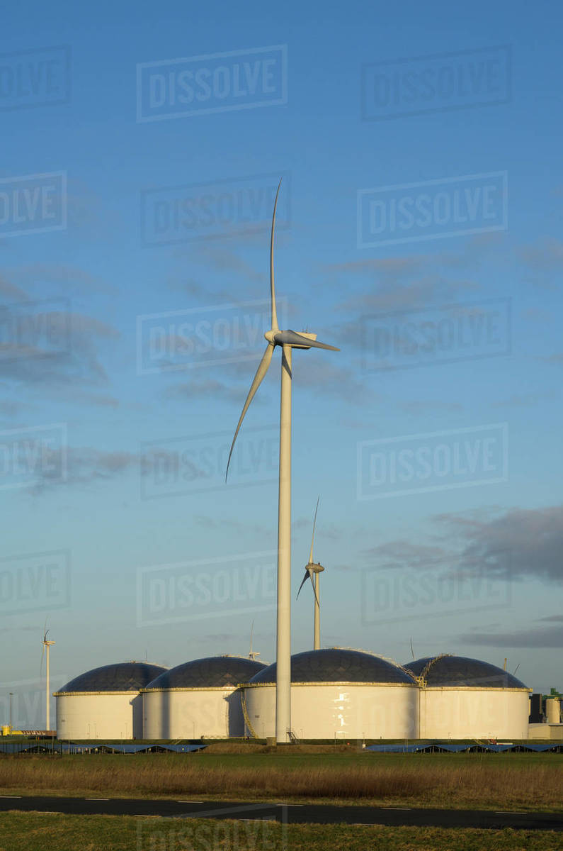 Netherlands, Eemshaven, Wind turbines and storage tanks in field ...
