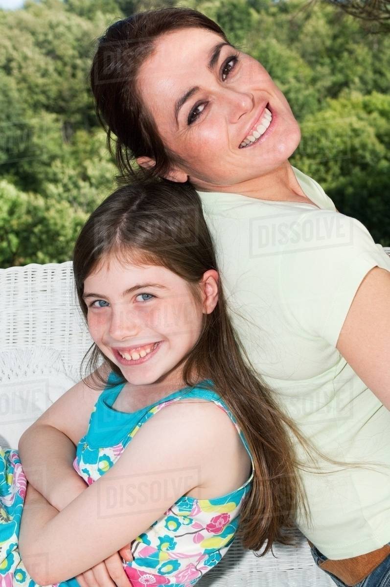 Mother and daughter back to back, portrait - Stock Photo - Dissolve