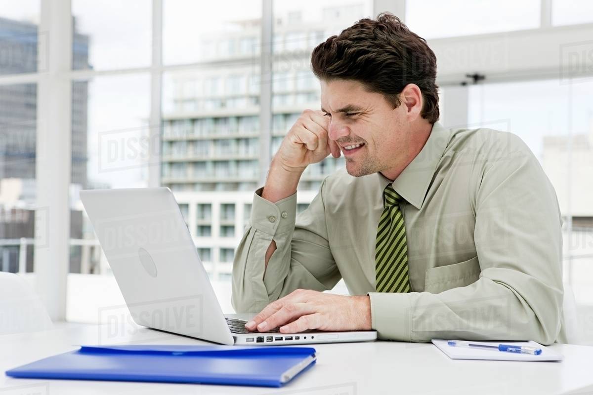 Businessman using laptop in office - Stock Photo - Dissolve