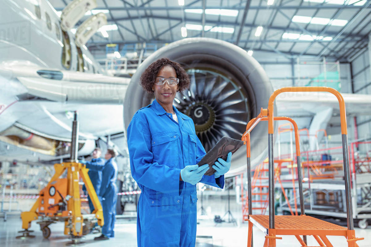 Portrait of female aircraft maintenance engineer in aircraft hangar ...