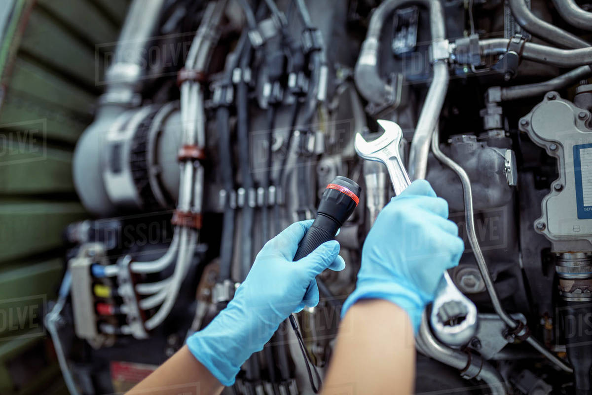Close-up of hands with tools and jet engine in aircraft maintenance ...