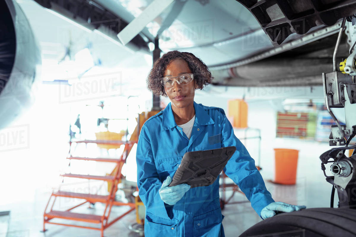 Female aircraft maintenance engineer underneath jet with digital tablet ...