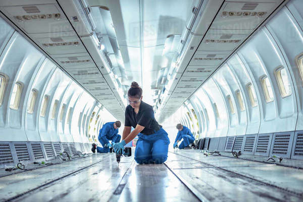Female apprentice aircraft maintenance engineer at work in empty ...