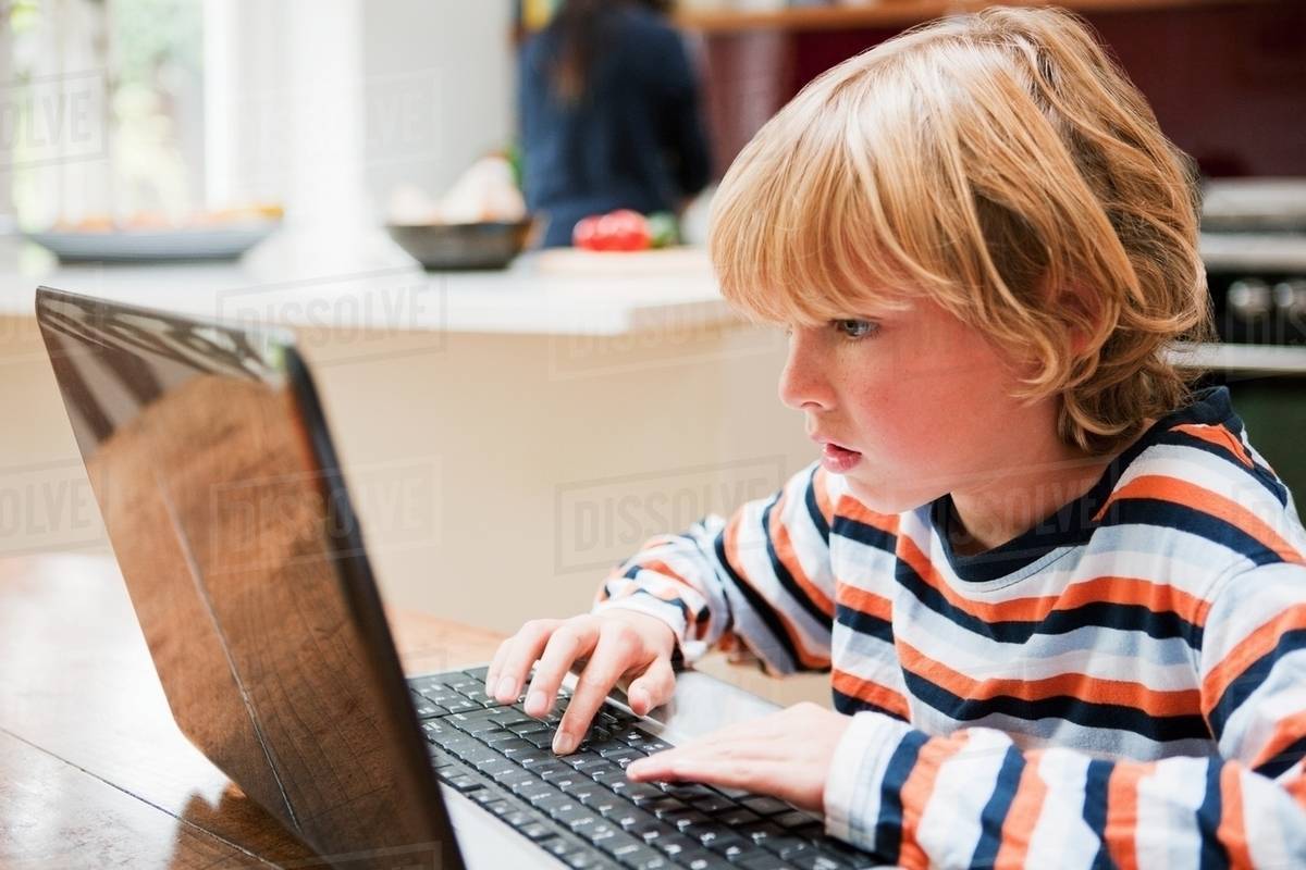 Young boy looking at a laptop monitor while typing - Royalty-free Stock ...