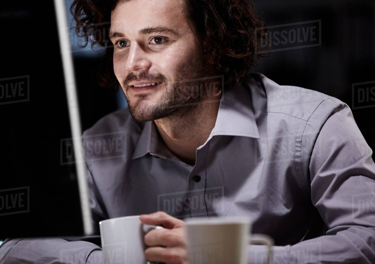 Young man looking at computer monitor, working late - Royalty-free ...