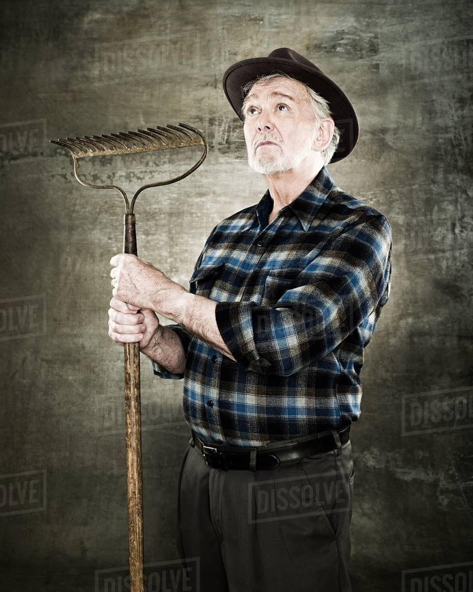 Portrait of a farmer holding a rake - Royalty-free Stock Photo | Dissolve