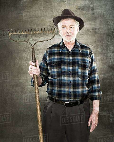 Portrait of a farmer holding a rake - Royalty-free Stock Photo | Dissolve
