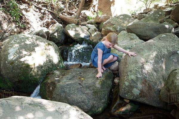 Girl on rocks by river - Stock Photo - Dissolve
