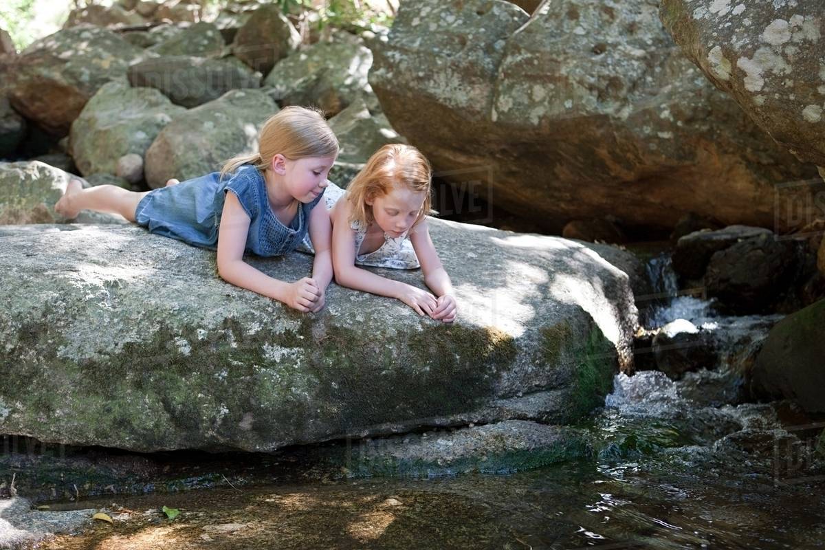 Girls lying on rock by river - Royalty-free Stock Photo | Dissolve