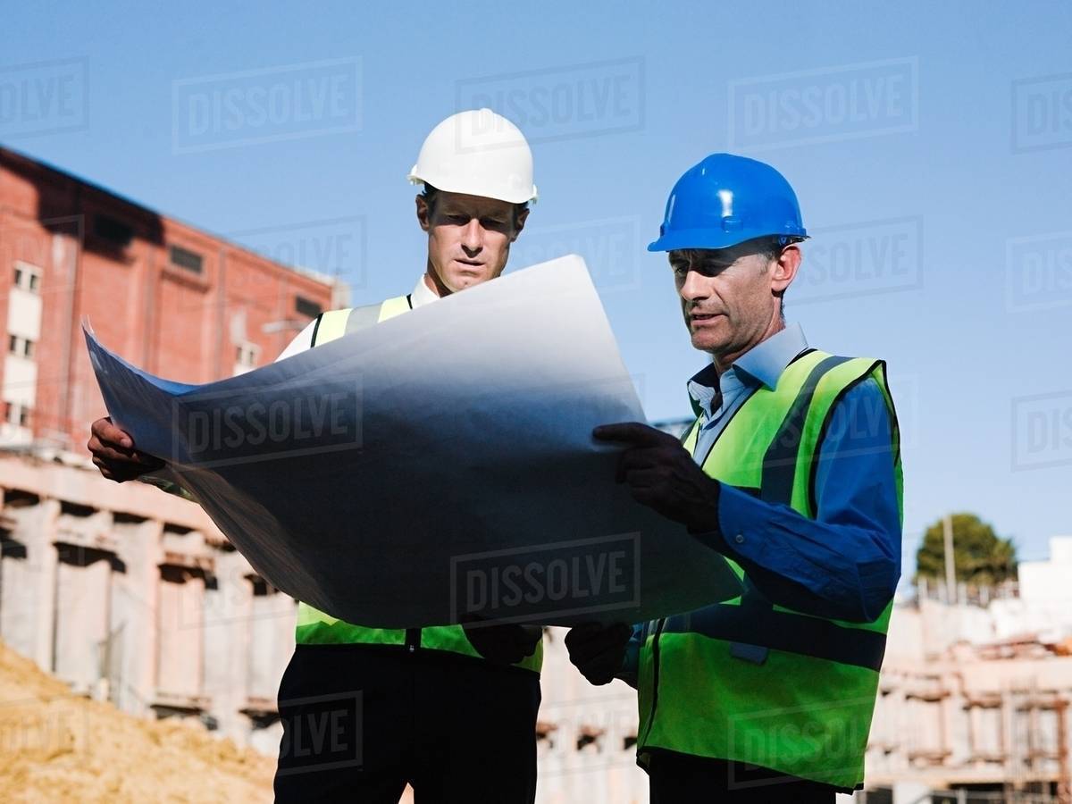 Mature men inspecting blueprints on construction site - Royalty-free ...