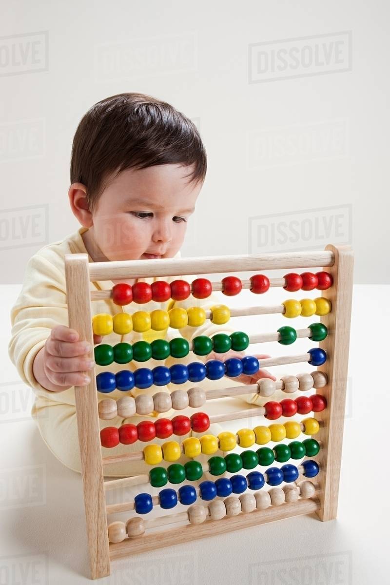 Baby boy playing with abacus - Stock Photo - Dissolve
