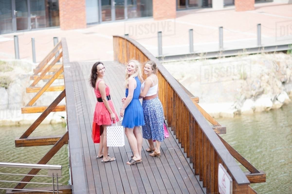Three young women walking over bridge - Stock Photo - Dissolve