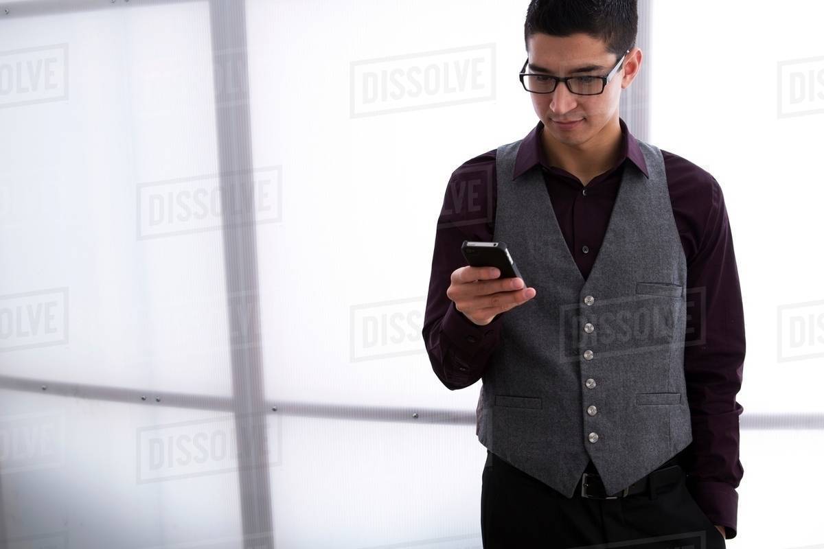 Young man texting on smartphone - Royalty-free Stock Photo | Dissolve