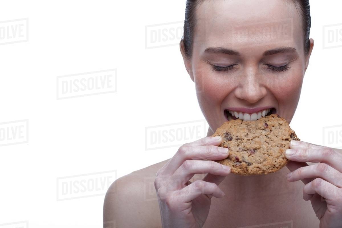 Young woman biting cookie - Stock Photo - Dissolve