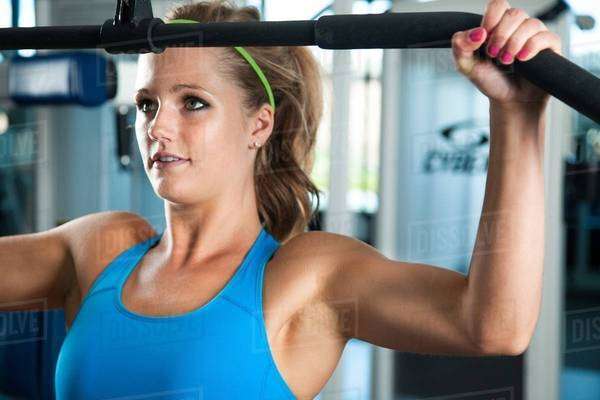 Close up of young woman pulling weights - Stock Photo - Dissolve