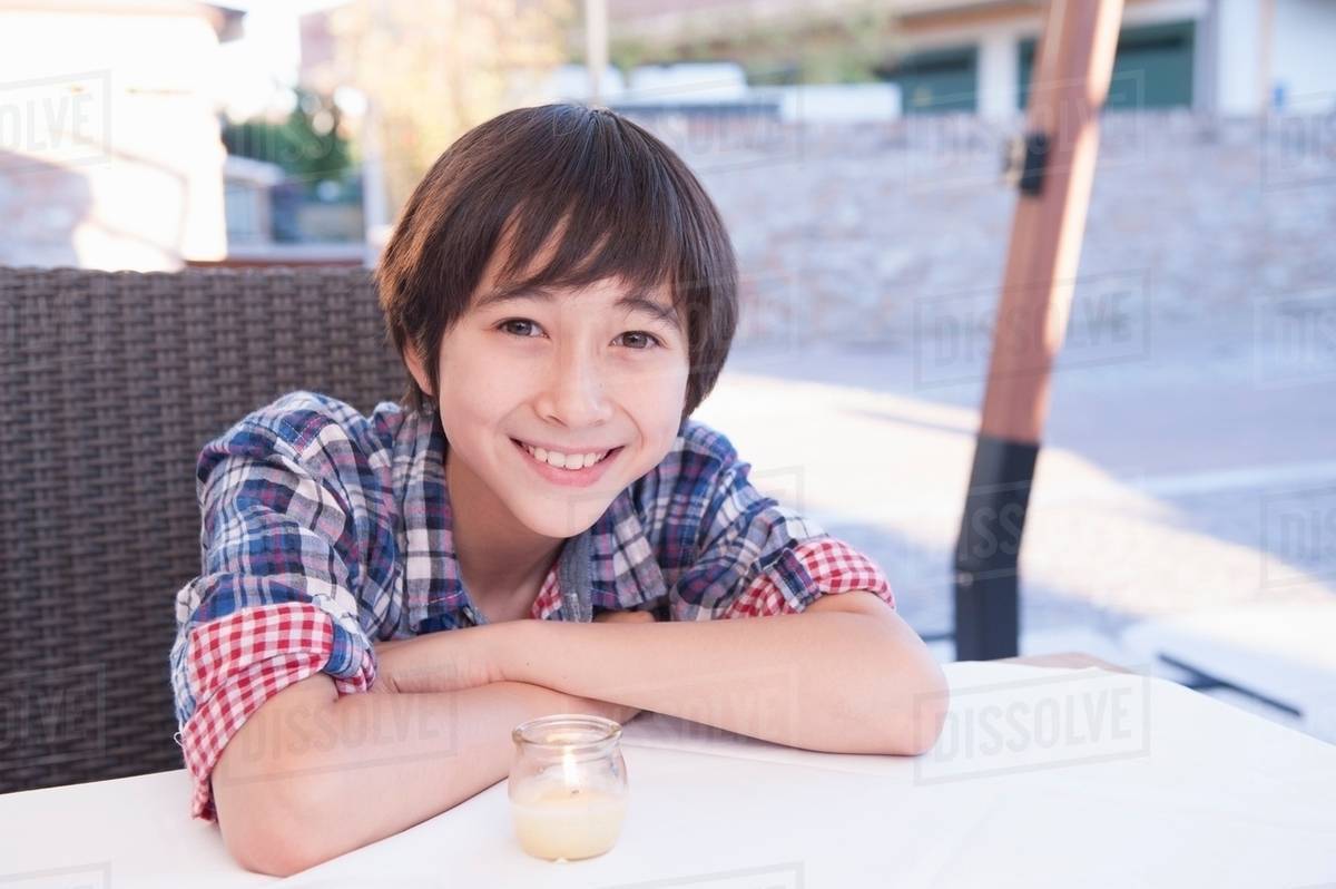 Boy leaning on table with tea light - Stock Photo - Dissolve