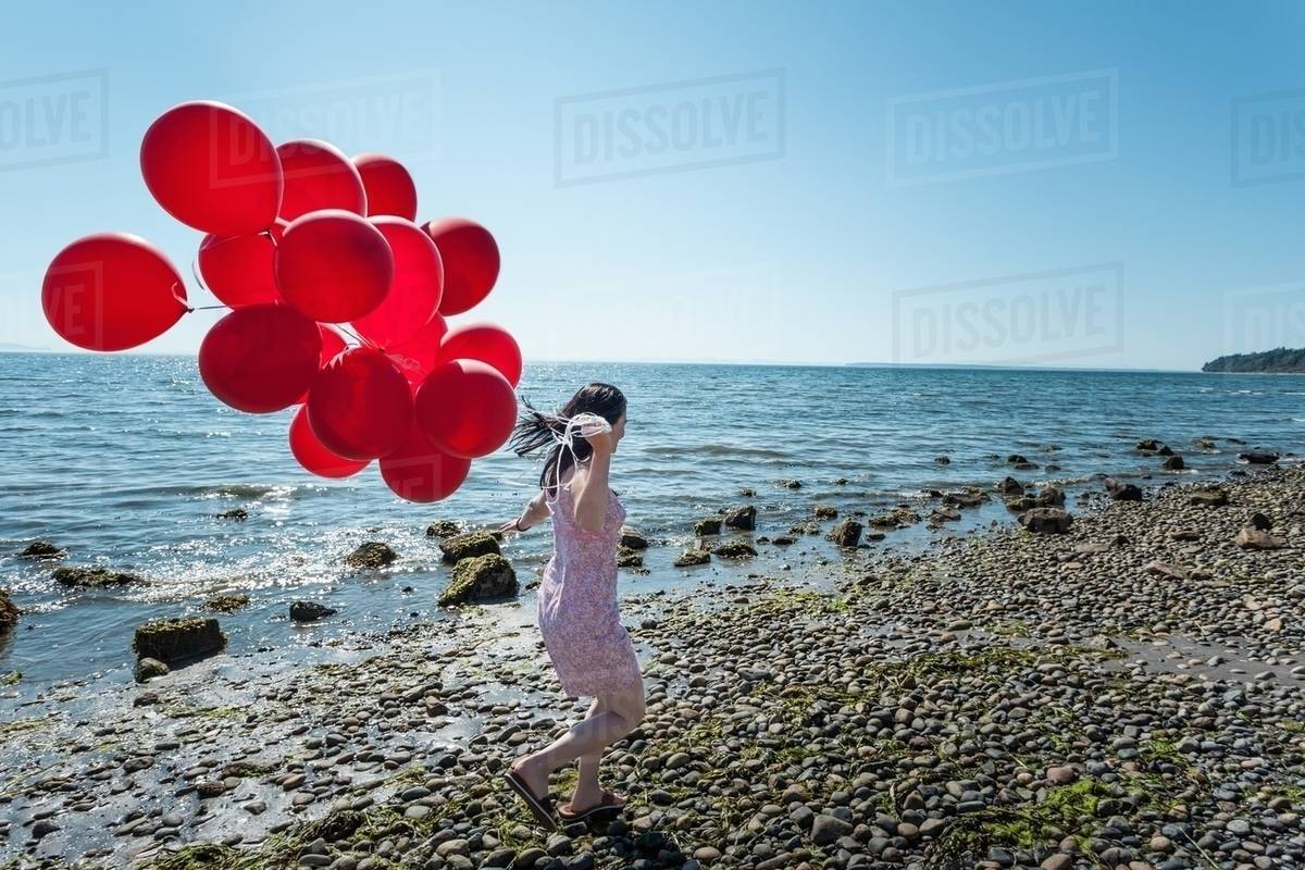 Mature woman pulling bunch of balloons - Stock Photo - Dissolve
