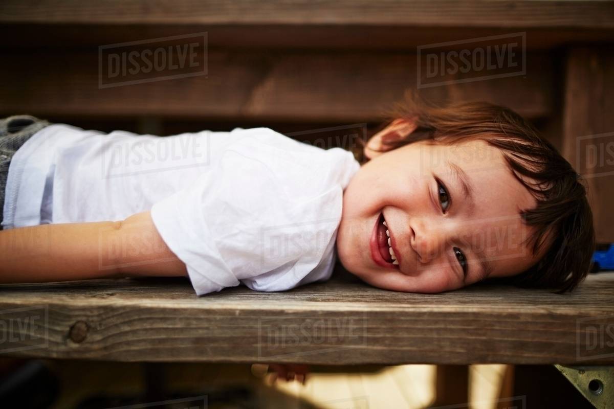 Portrait of smiling boy laying on bench - Royalty-free Stock Photo ...